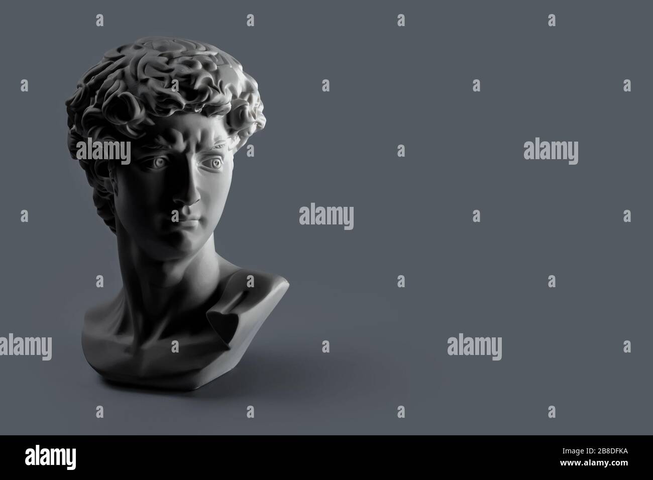 Gypsum statue of David's head. Michelangelo's David statue plaster copy on dark grey background ...