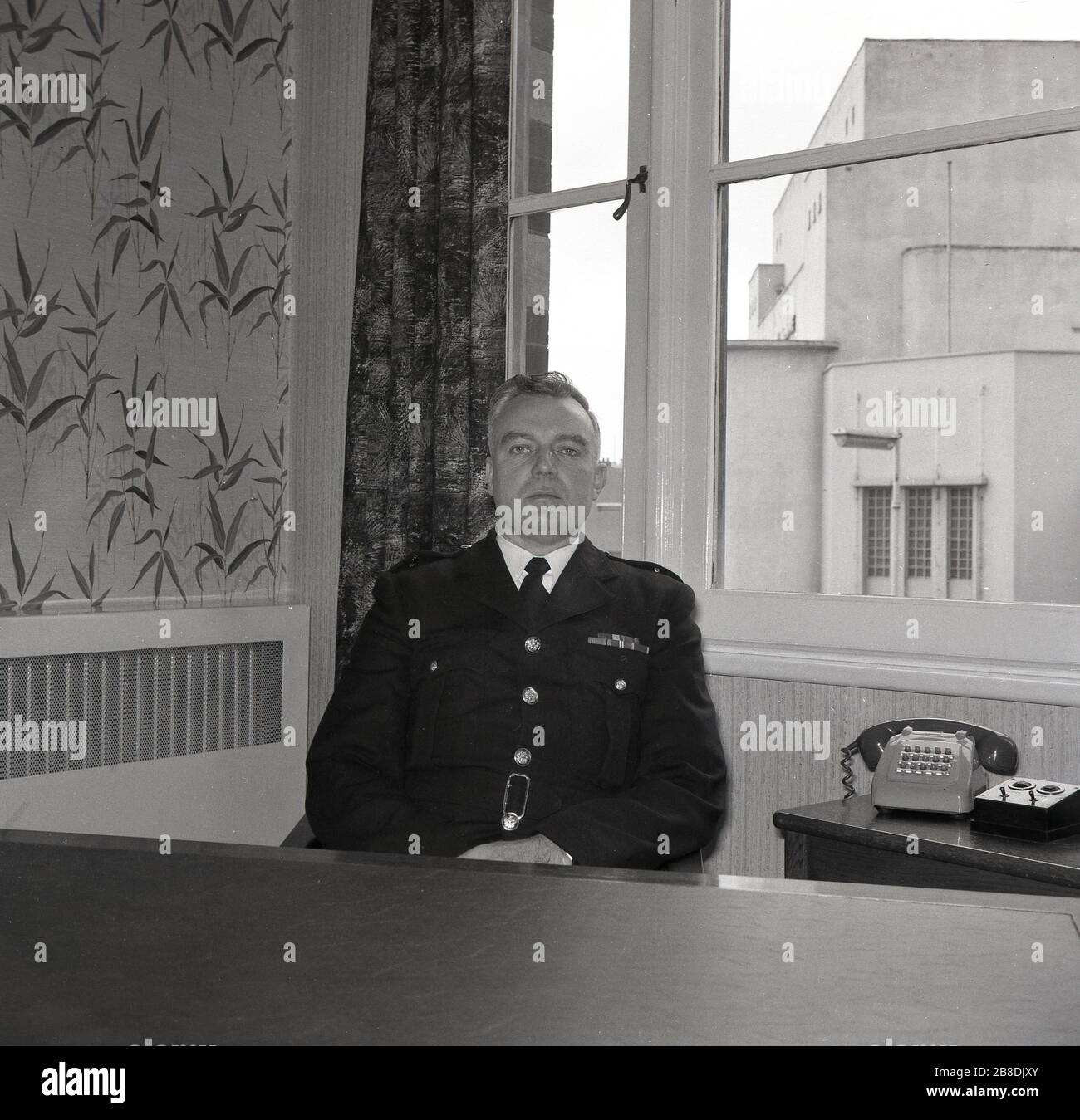 1967, historical, Uniformed French police inspector sitting at a ...