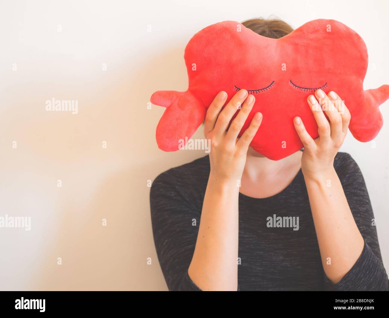 Faceless woman covering face with red heart toy Stock Photo - Alamy