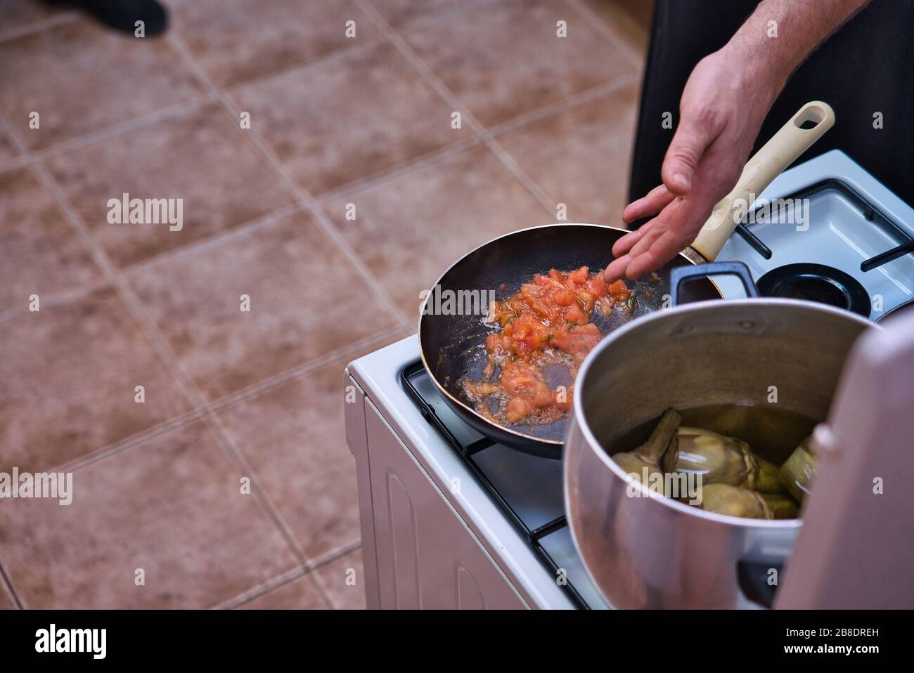 Cooking a homemade tomato sauce in a frying pan on a gas fire and ...