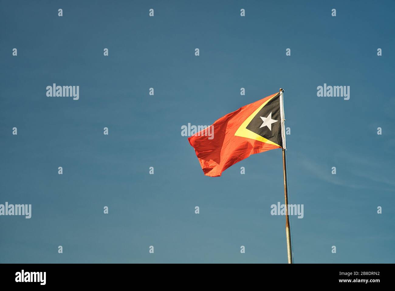 Timor Leste ( East Timor ) flag waving on the mastg. Blue background ...