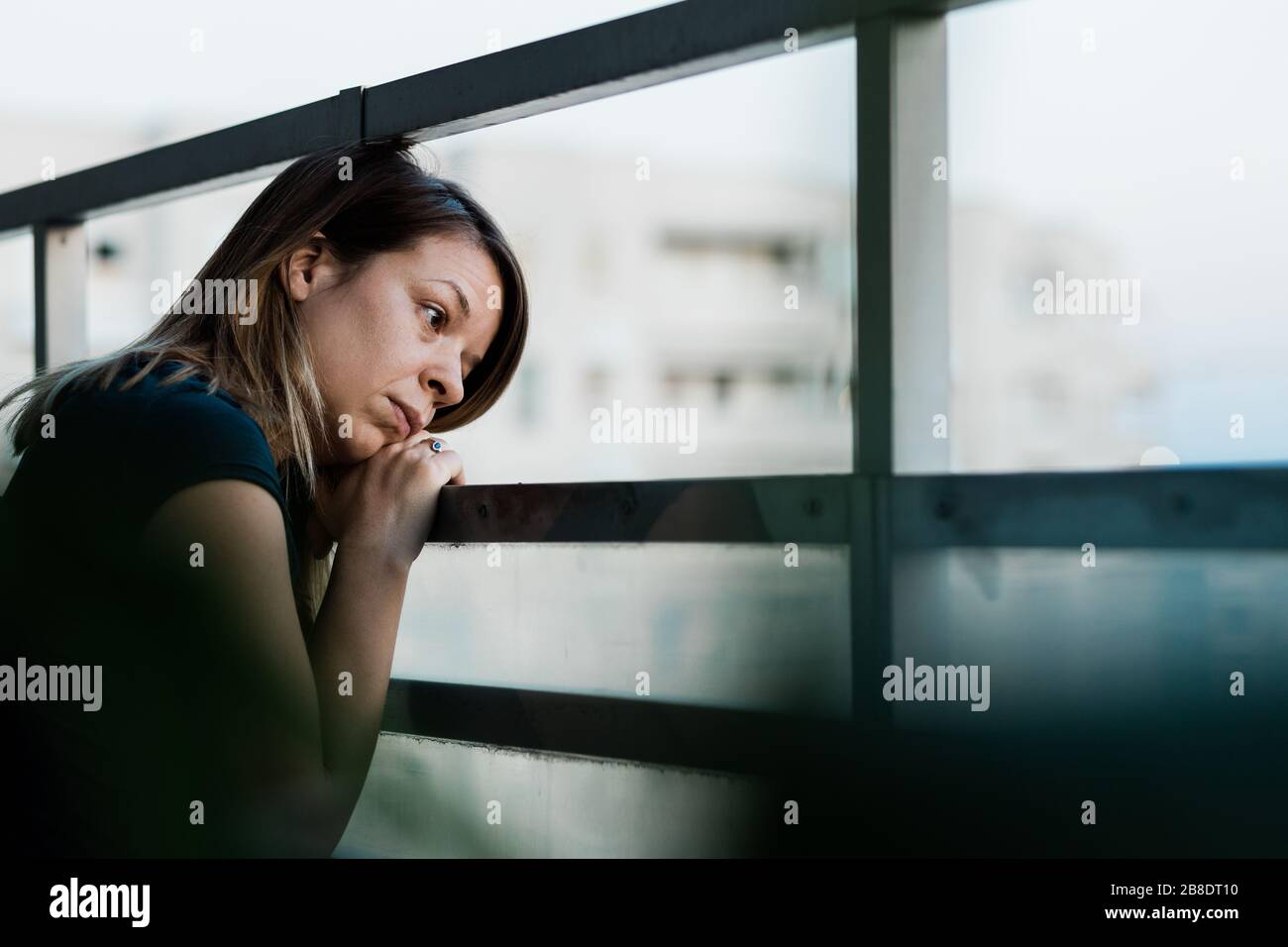 Young sad woman looking outside through balcony of an apartment ...