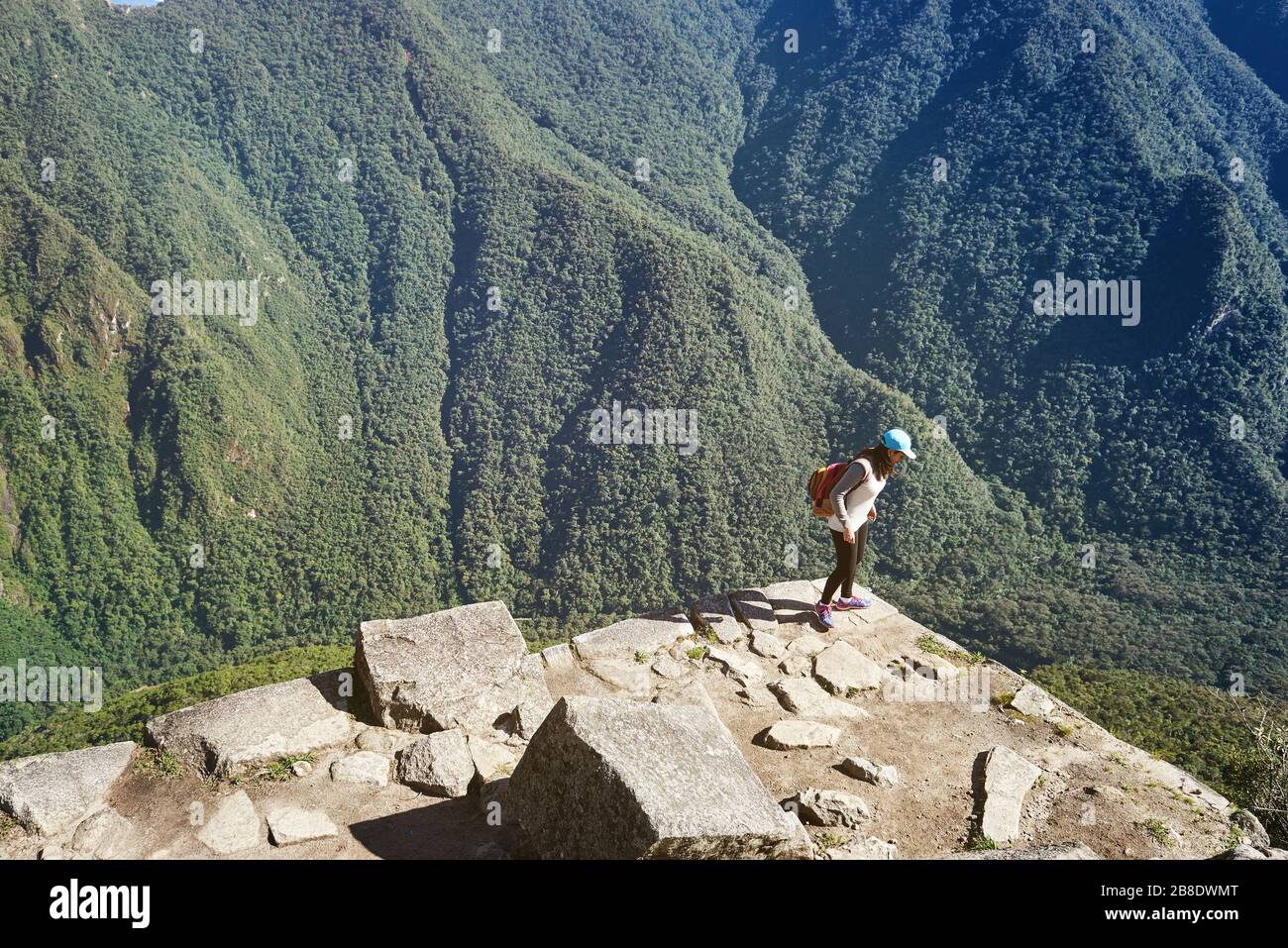 Woman looking down from mountain cliff above view Stock Photo - Alamy