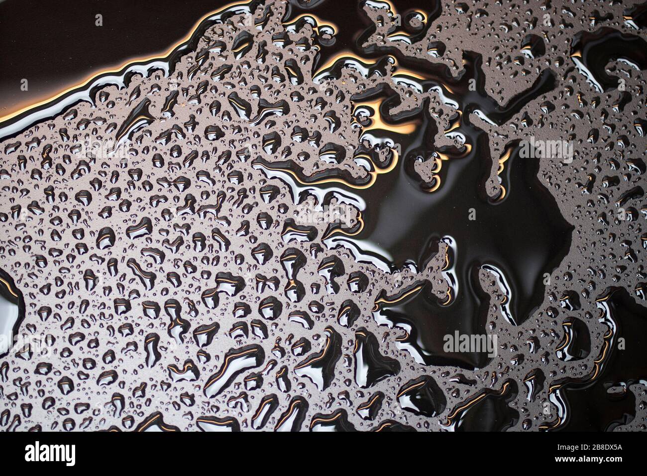 Drops of rain on the surface of a black lacquered table with ...
