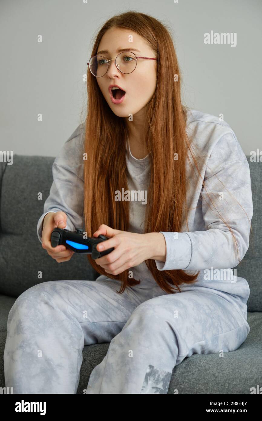 A red-haired girl with glasses, with long tails, sits on a devan with a ...