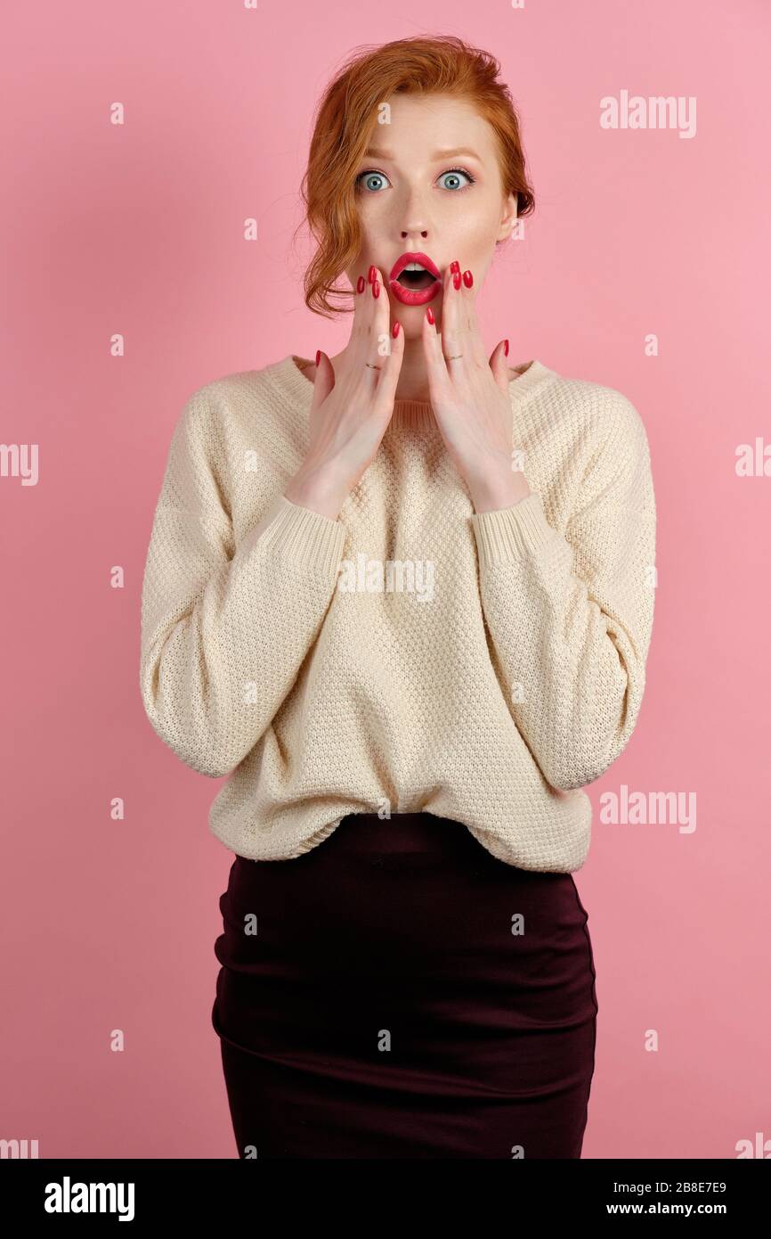 Redhead girl with red lipstick and red manicure looks shocked at the ...