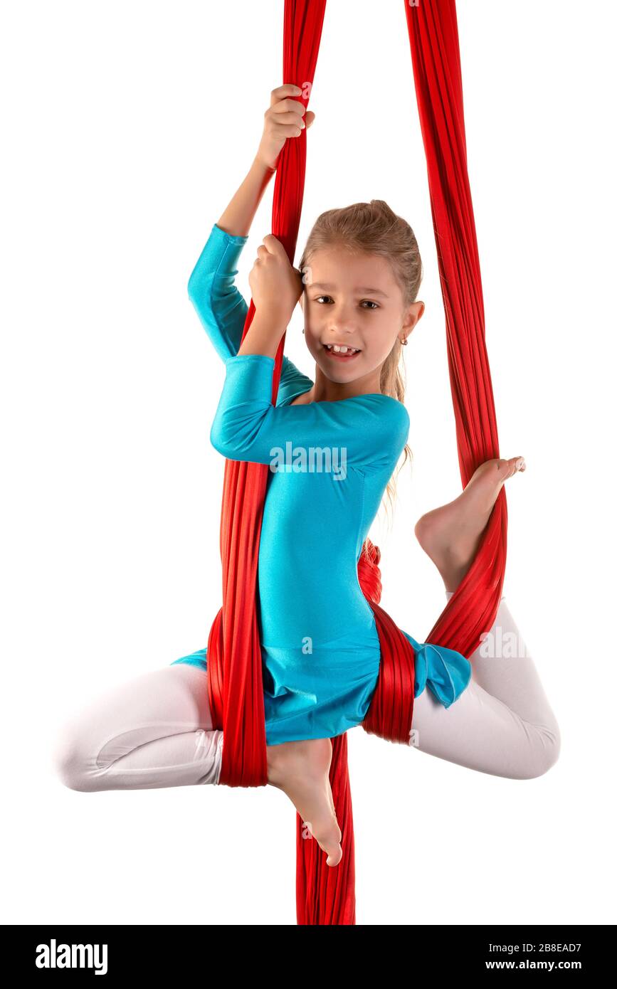 Cheerful pretty little girl in a blue gymnastic suit does tricks in a ...