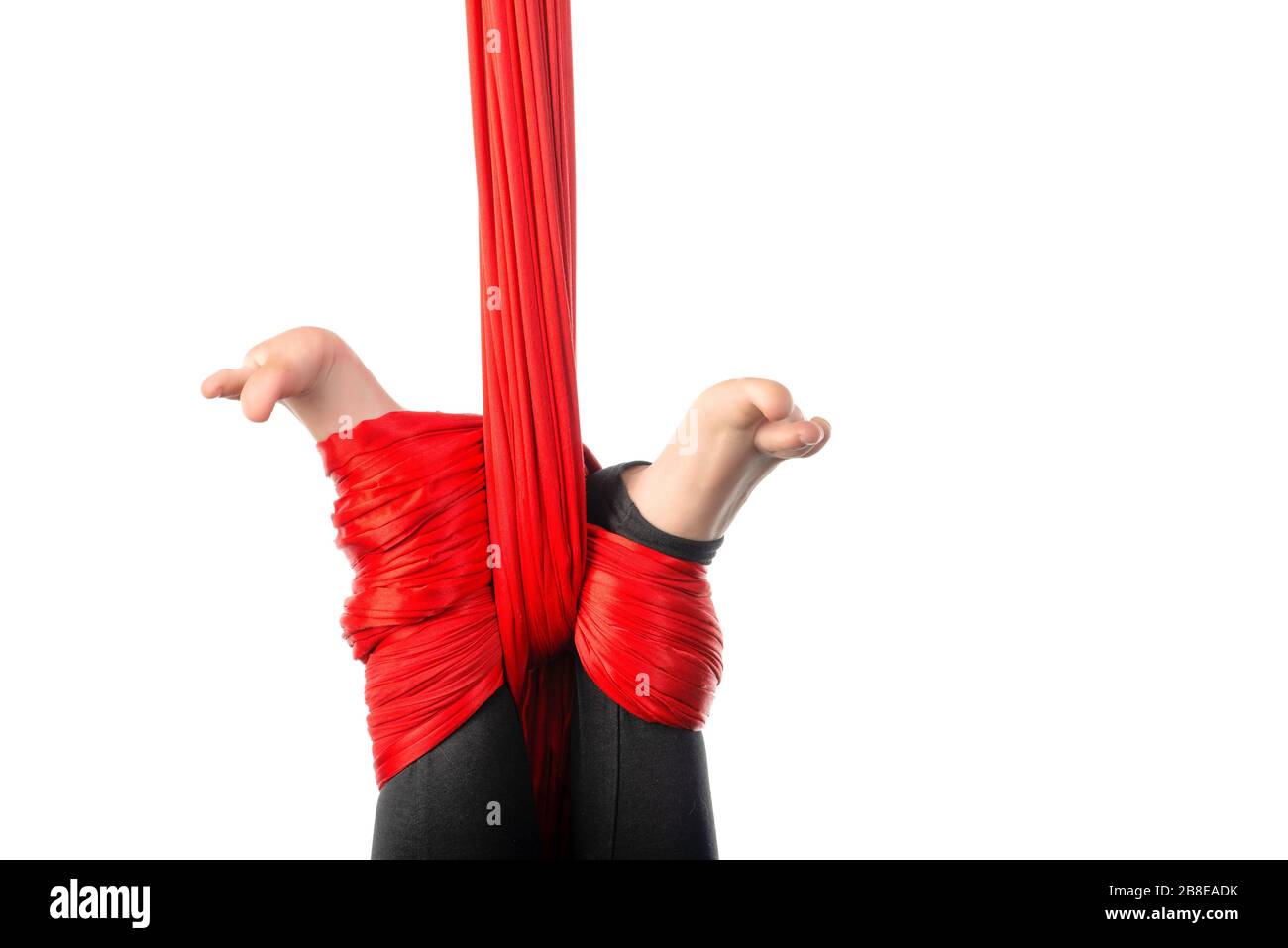 Close-up of a little girl's legs tied in a knot of red airy ribbons on ...