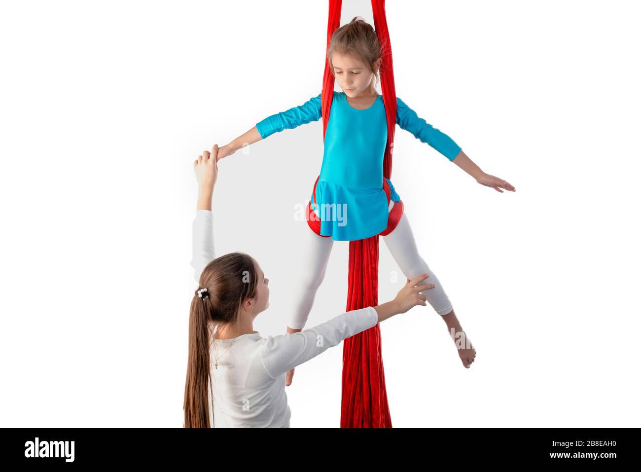 Teenage girl helps her little sister to properly fix herself on red air ...