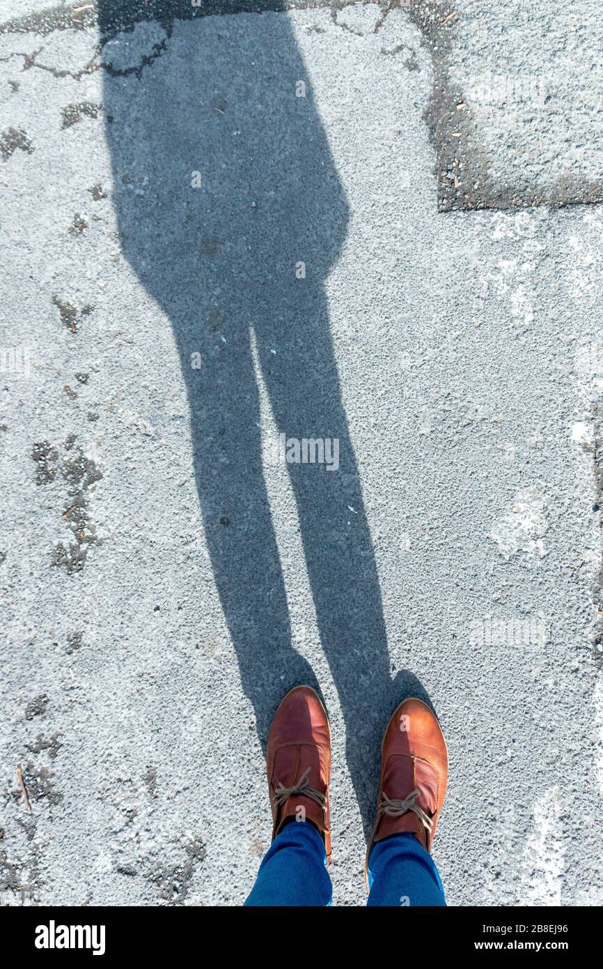 a close up view of a ladys shadow the bottom of her legs and shoes ...