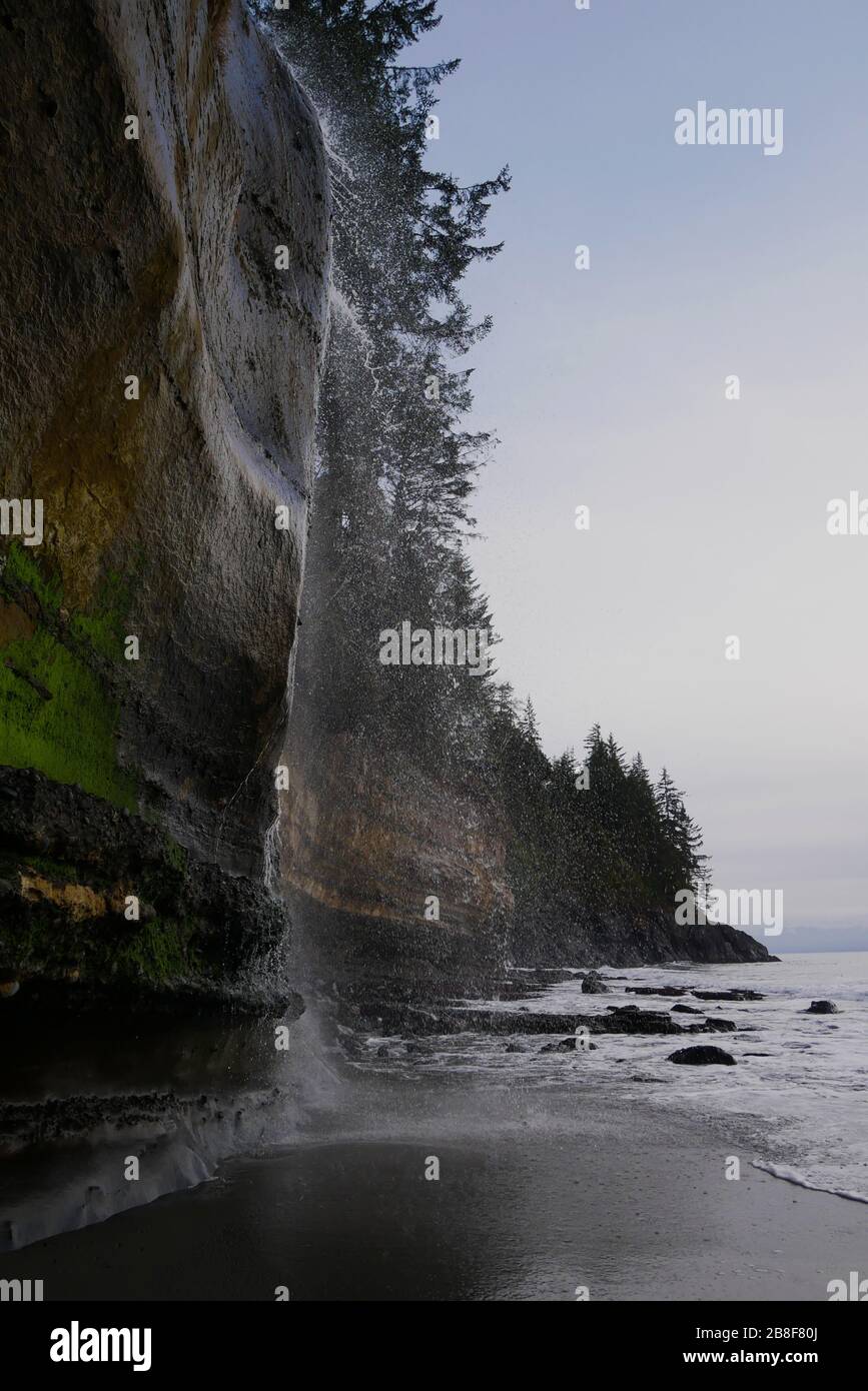 Waterfall on Canadian beach with colorful layers of rock in cliff Stock ...