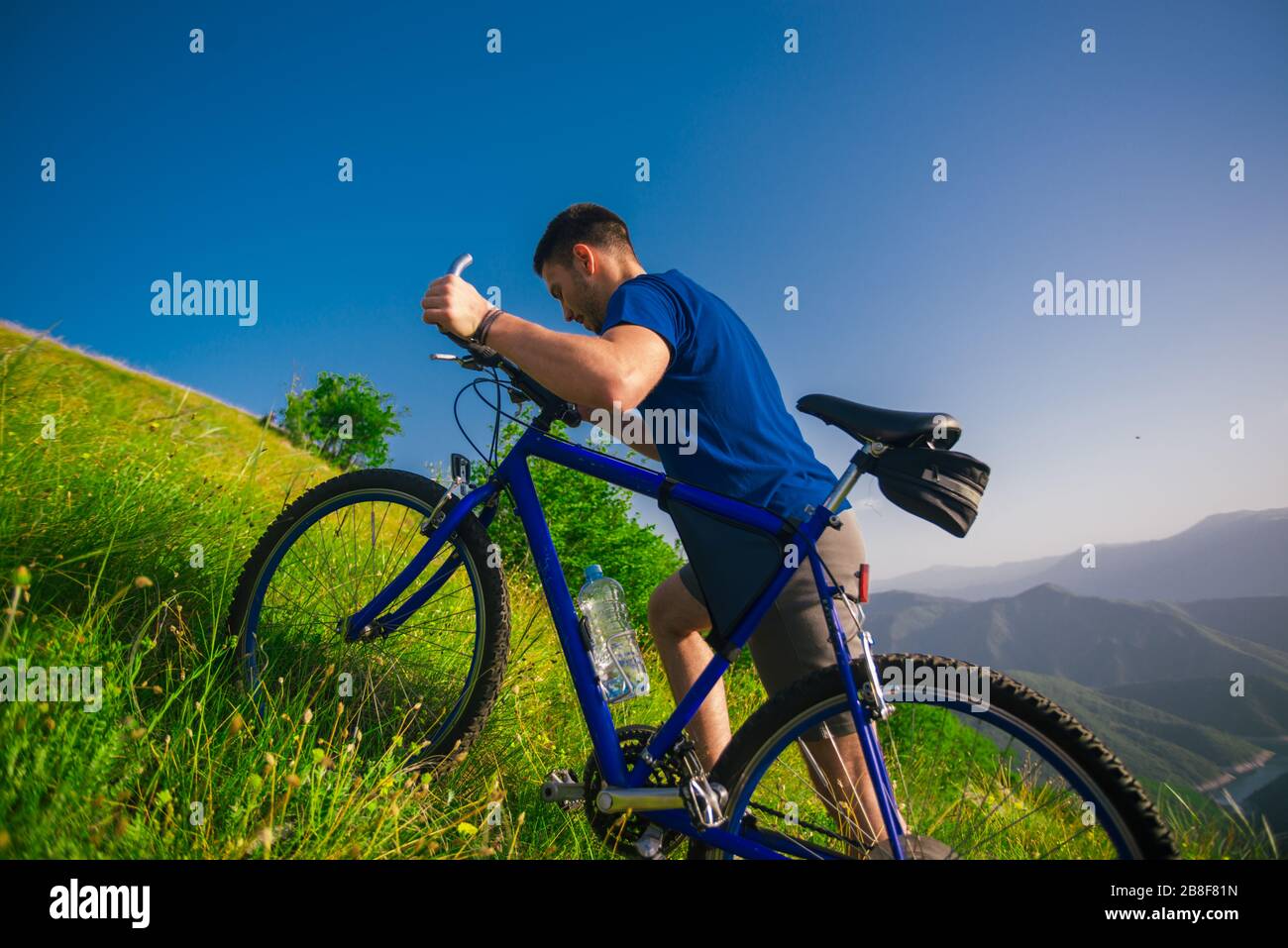Perspective of a fit mountain biker pushing his bike uphill with ...