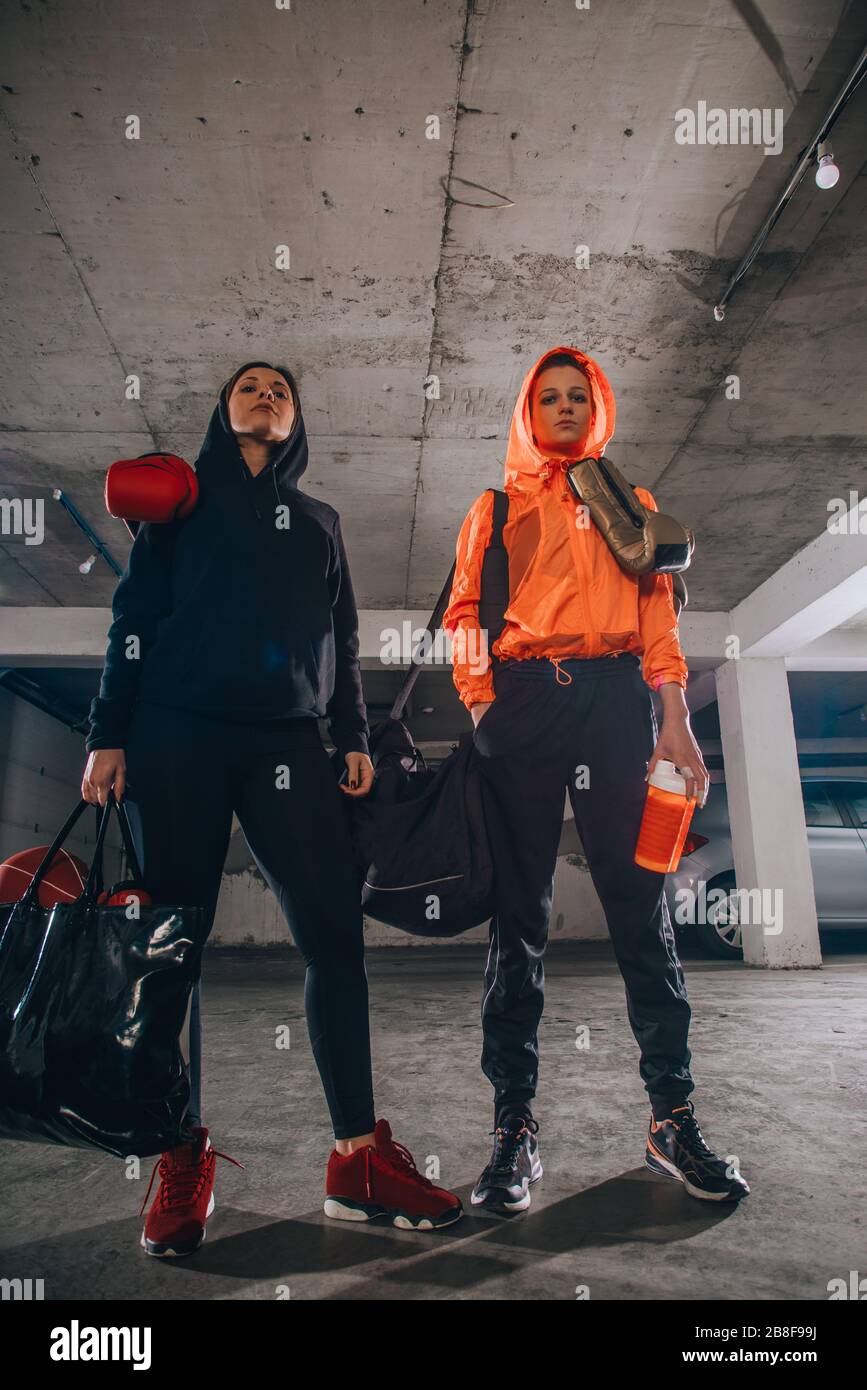 Two female boxer friends standing in a garage with boxing equipment ...