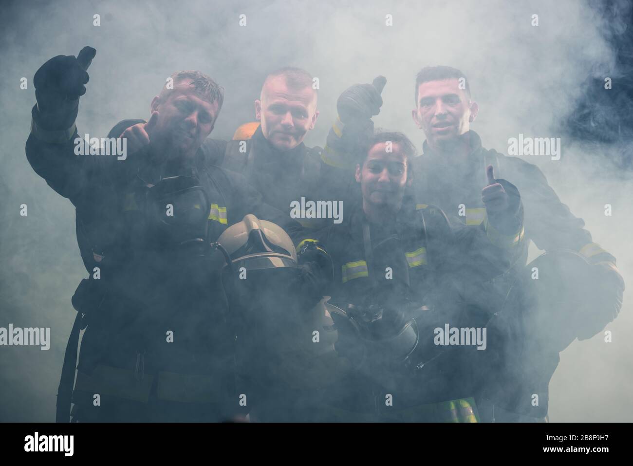 Team of firefighters standing the middle of the fire extinguisher's ...