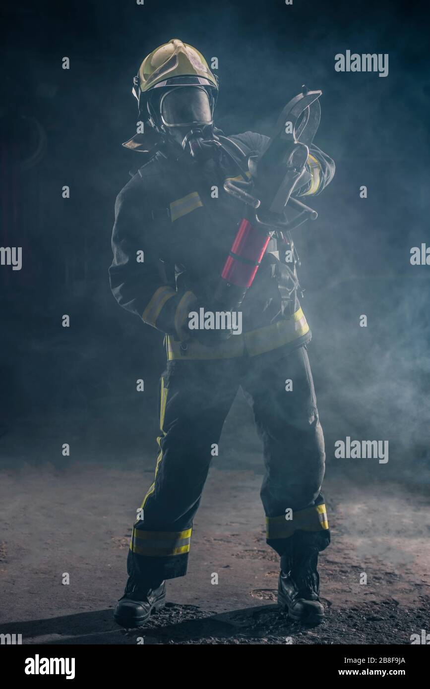 Portrait of a fireman wearing firefighter turnouts and helmet. Dark ...