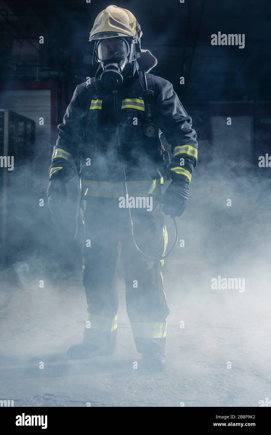 Portrait of a fireman wearing firefighter turnouts and helmet. Dark ...