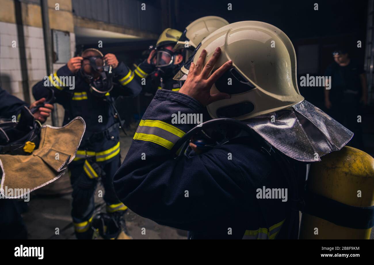Group of firefighters standing inside the fire brigade wearing helmet ...