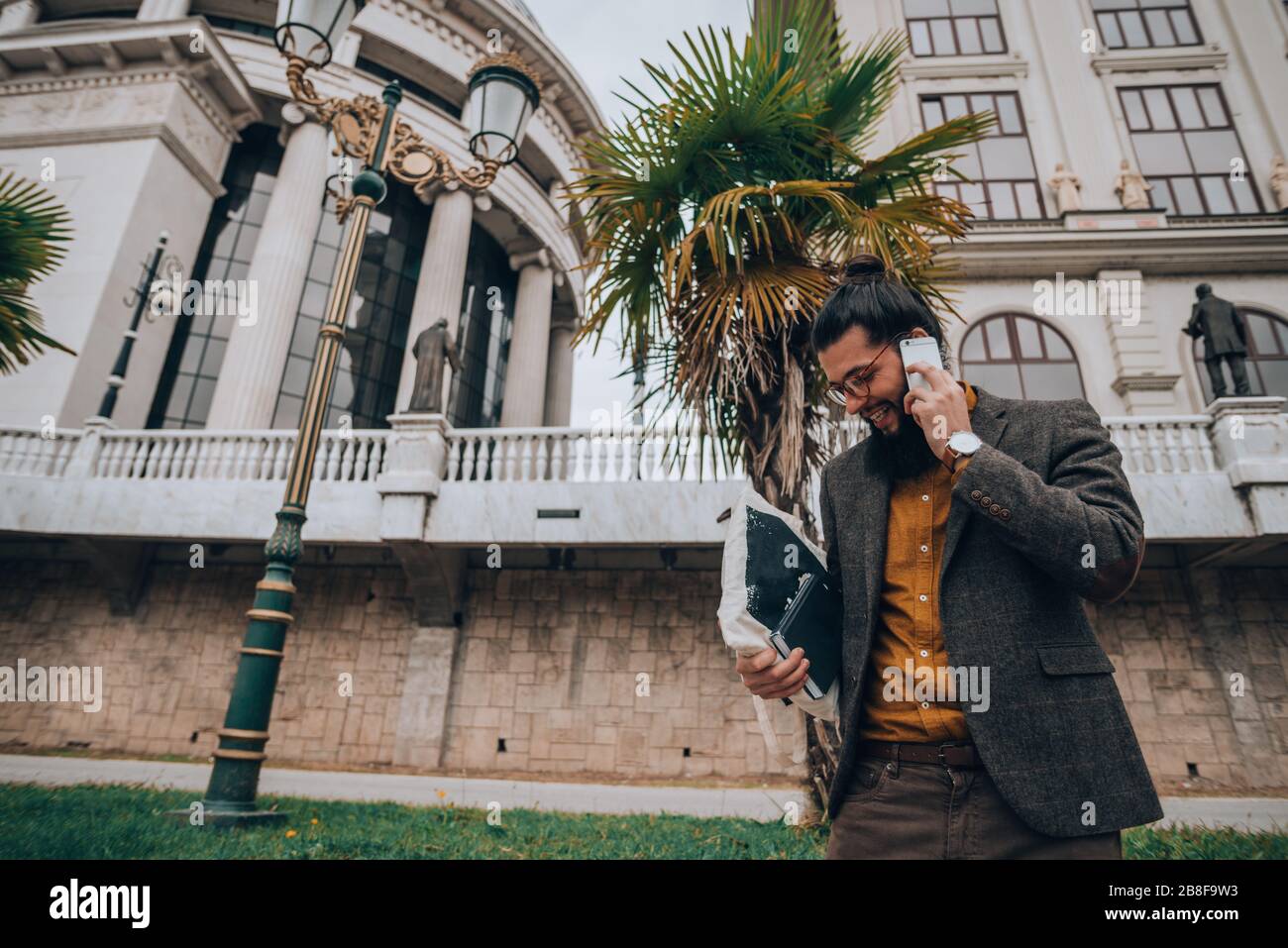 Modern hipster guy with long hair and beard at the city promenade ...