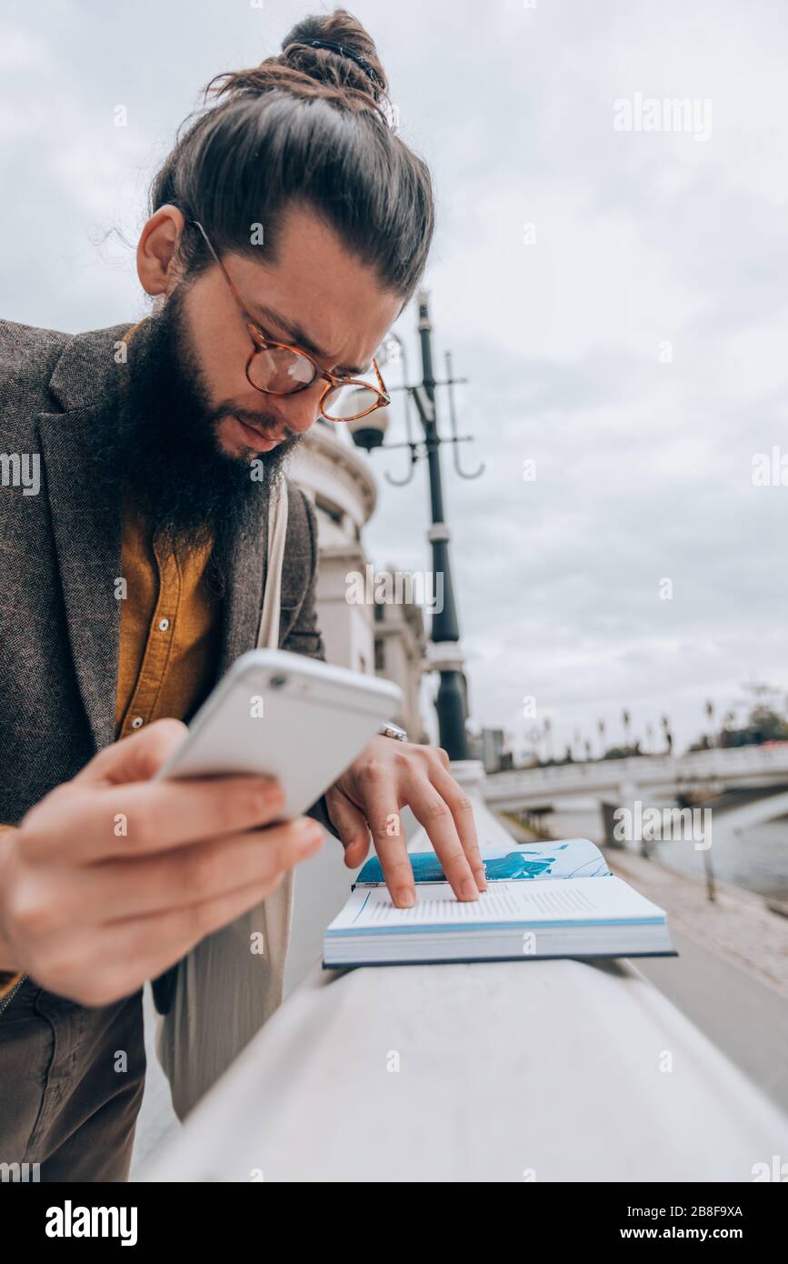 Stylish caucasian male clothed in a fashionable outfit reading a book ...