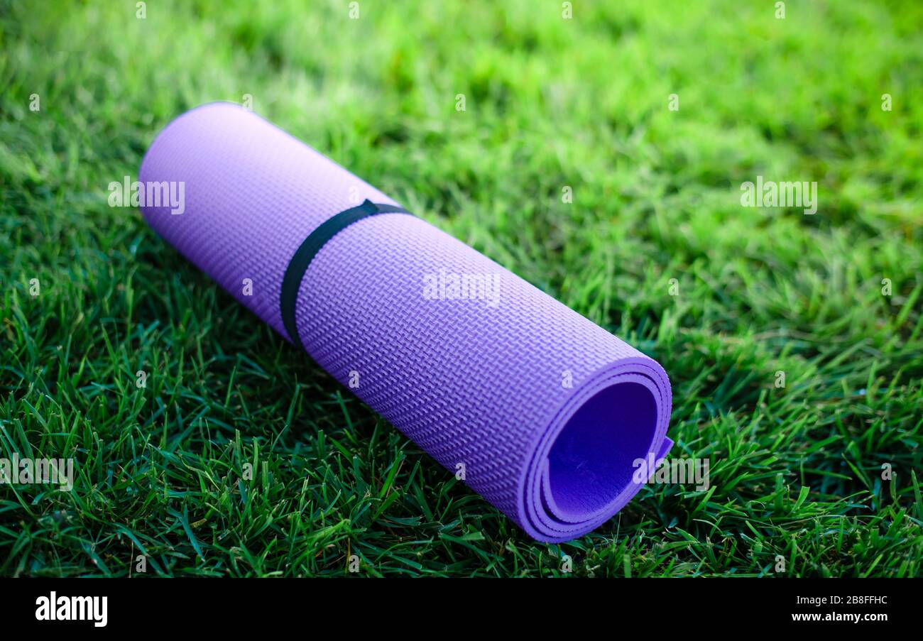 Close up Yoga mat roll on green grass ready for practice and relax with ...