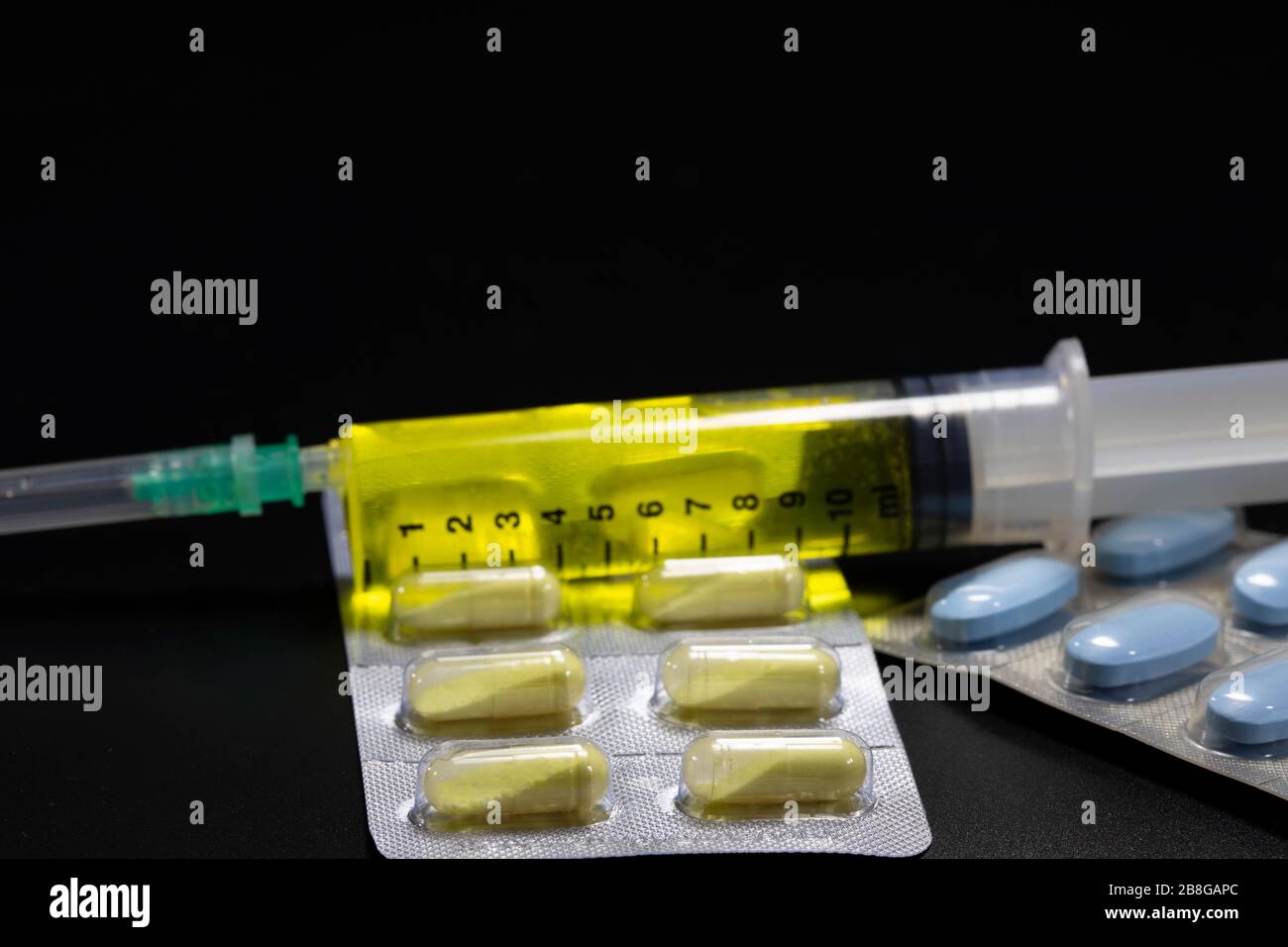 Round pills and syringe with yellow liquid inside Stock Photo - Alamy