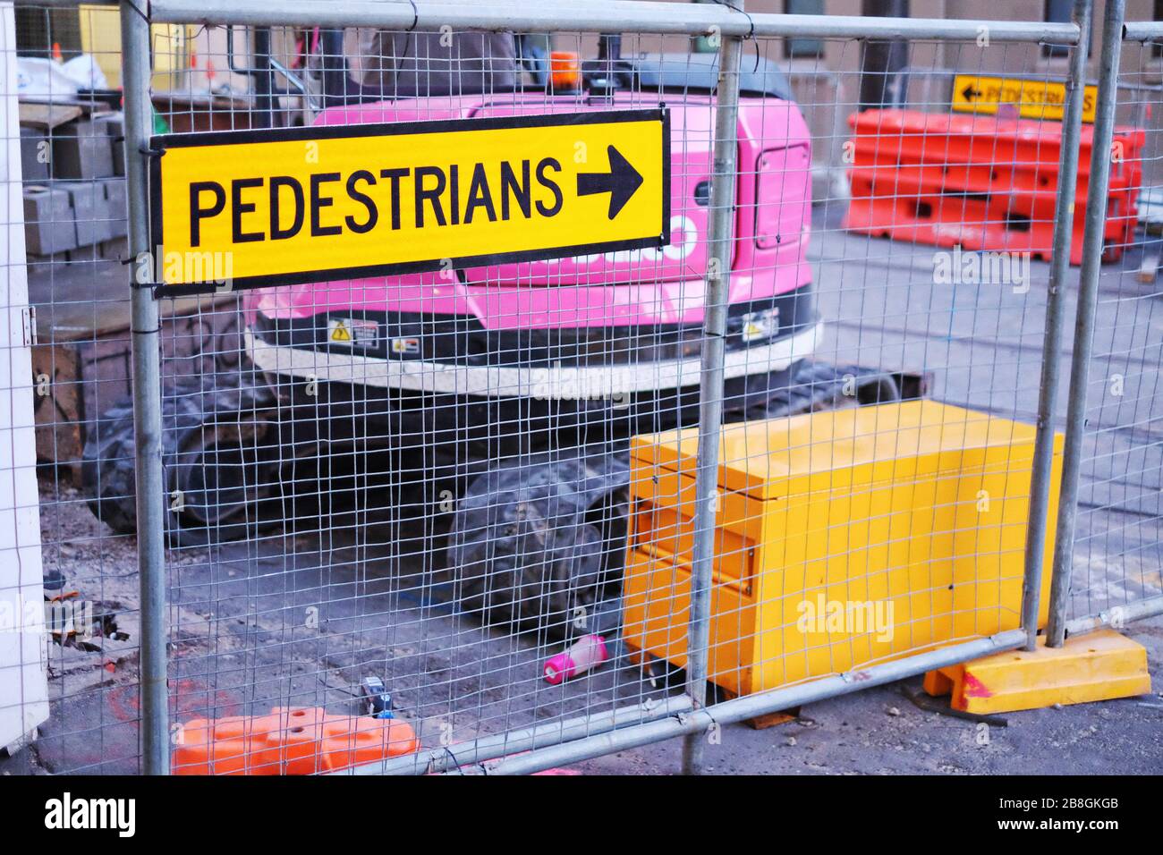 Pedestrians sign on an wire mesh construction fence at an on-street ...