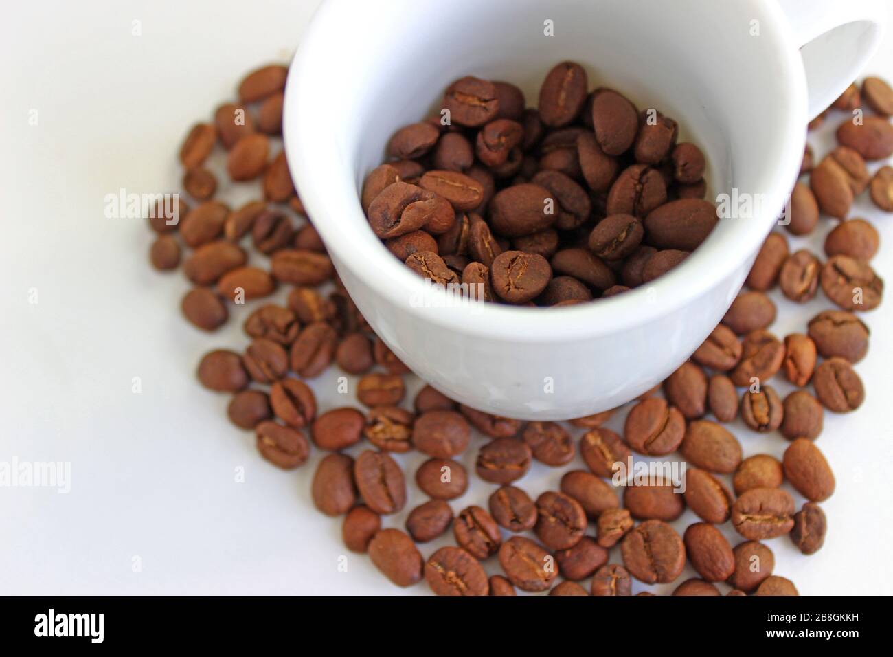 Spilled coffee beans from the white ceramic cup isolated on white ...