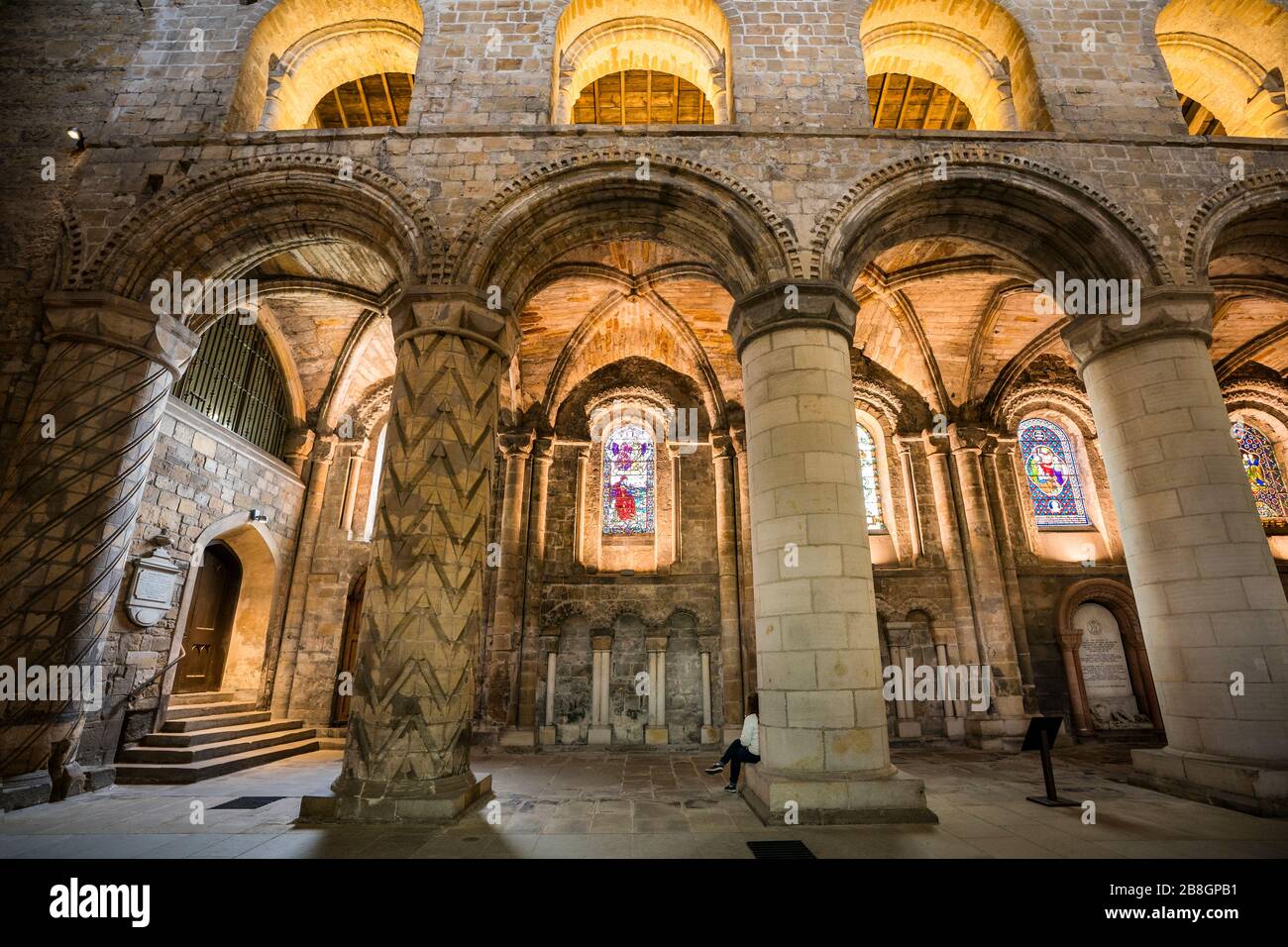 Female tourist sits at base of a carved pillar admiring the stained ...