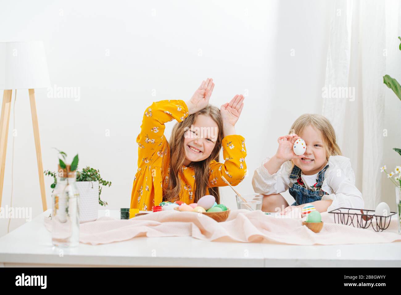 Two little girls sitting behind a table with easter eggs Stock Photo ...