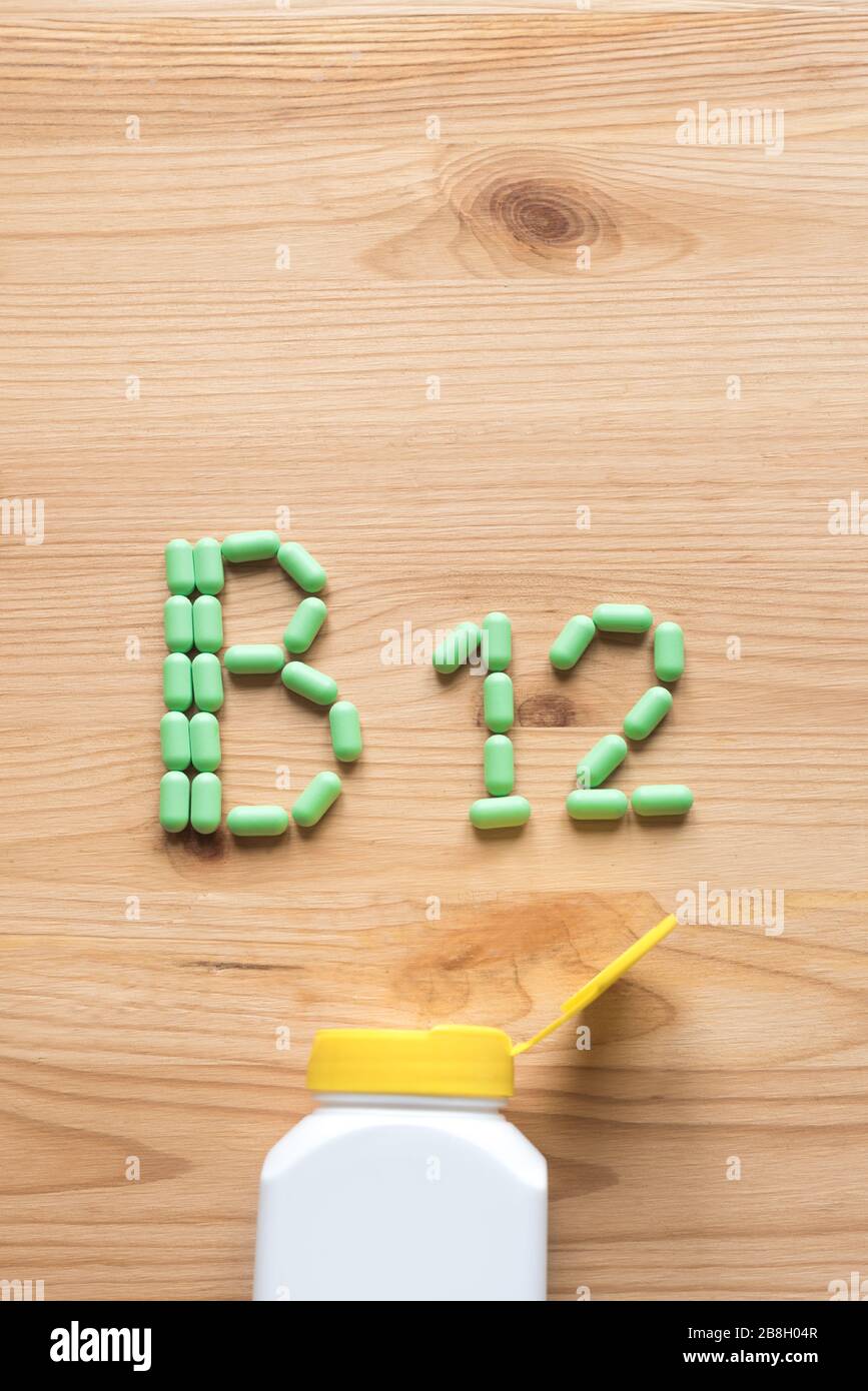 Vitamin B12. Green pills forming shape to B12 alphabet on wooden ...