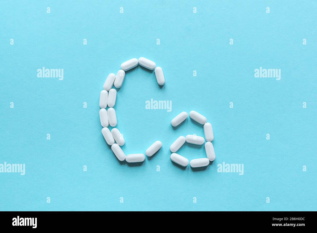 Calcium Tablets. White pills forming shape to Ca alphabet on blue ...
