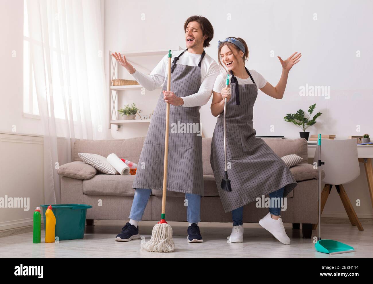 Couple Having Fun While Cleaning Home, Playing With Mop And Broom Stock ...