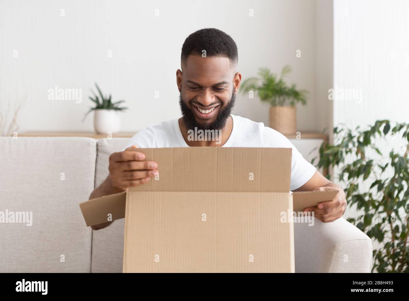 Online shopping at home. Smiling guy unpack delivery Stock Photo - Alamy