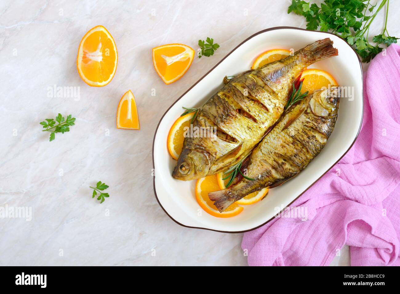 Baked roach fish with vegetables and oranges in a ceramic bowl. Top ...