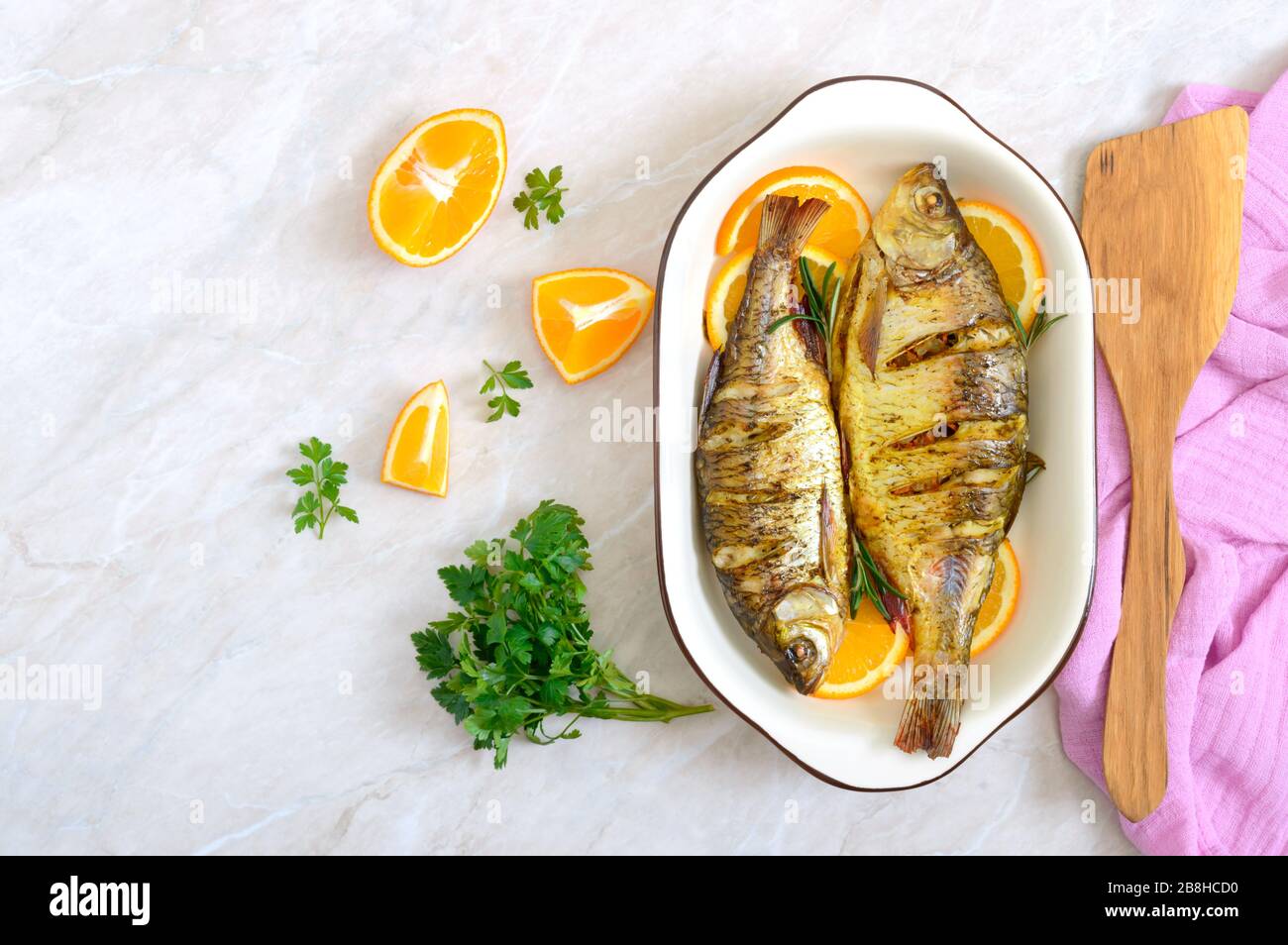 Baked roach fish with vegetables and oranges in a ceramic bowl. Top ...