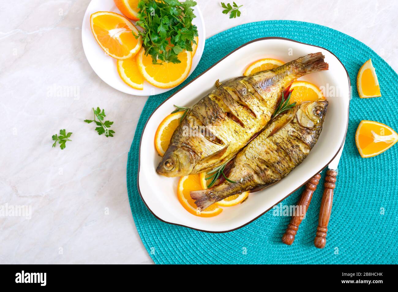 Baked roach fish with vegetables and oranges in a ceramic bowl. Top ...