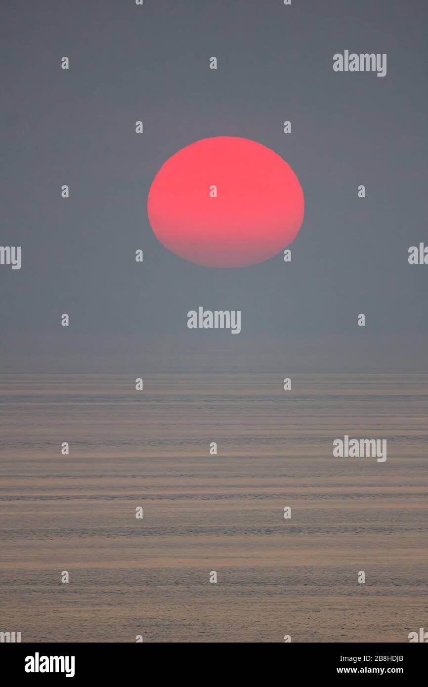 The sun is falling into the sea and being partially swallowed by the ...