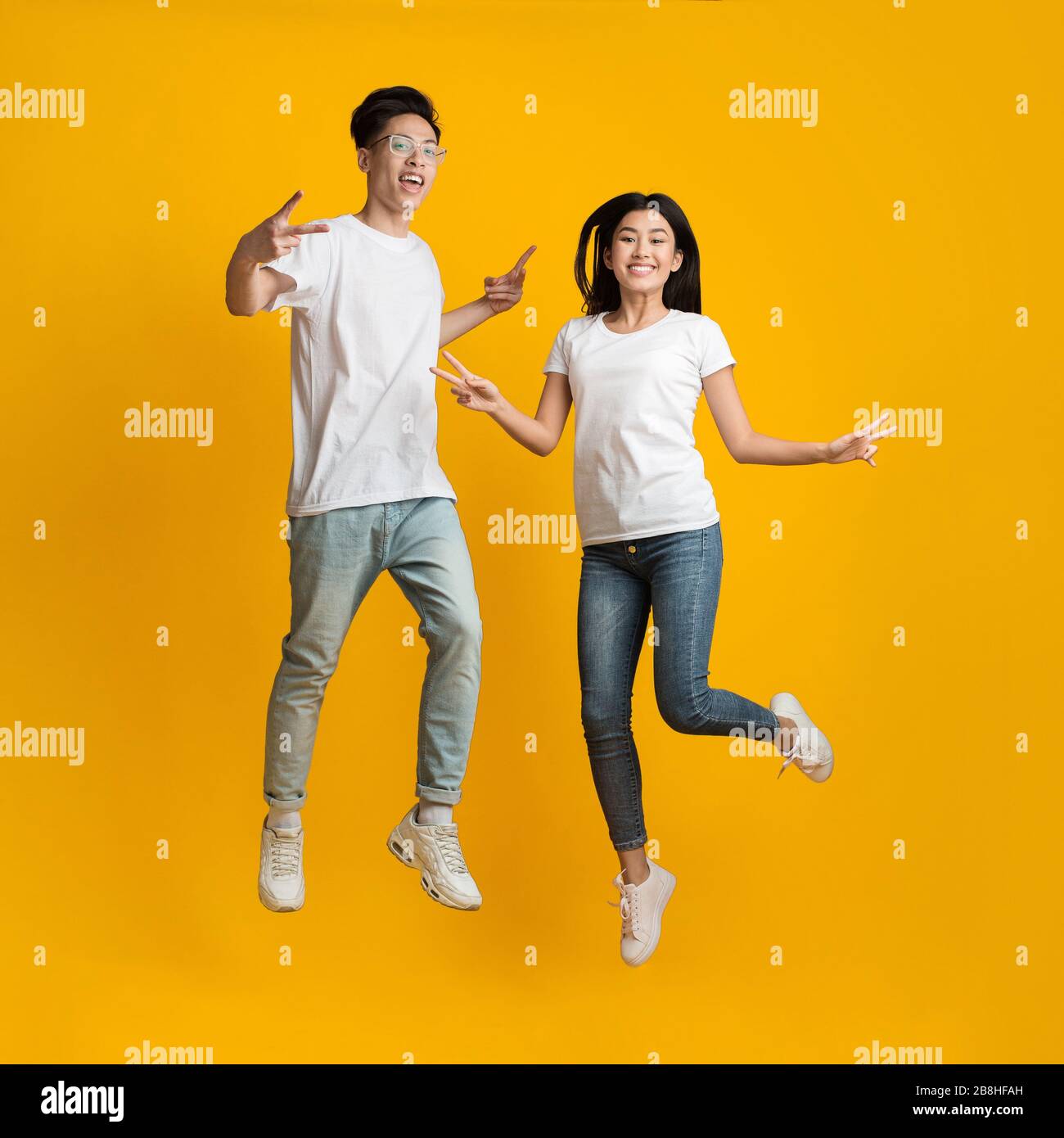 Happy young asian man and woman jumping up while posing Stock Photo - Alamy