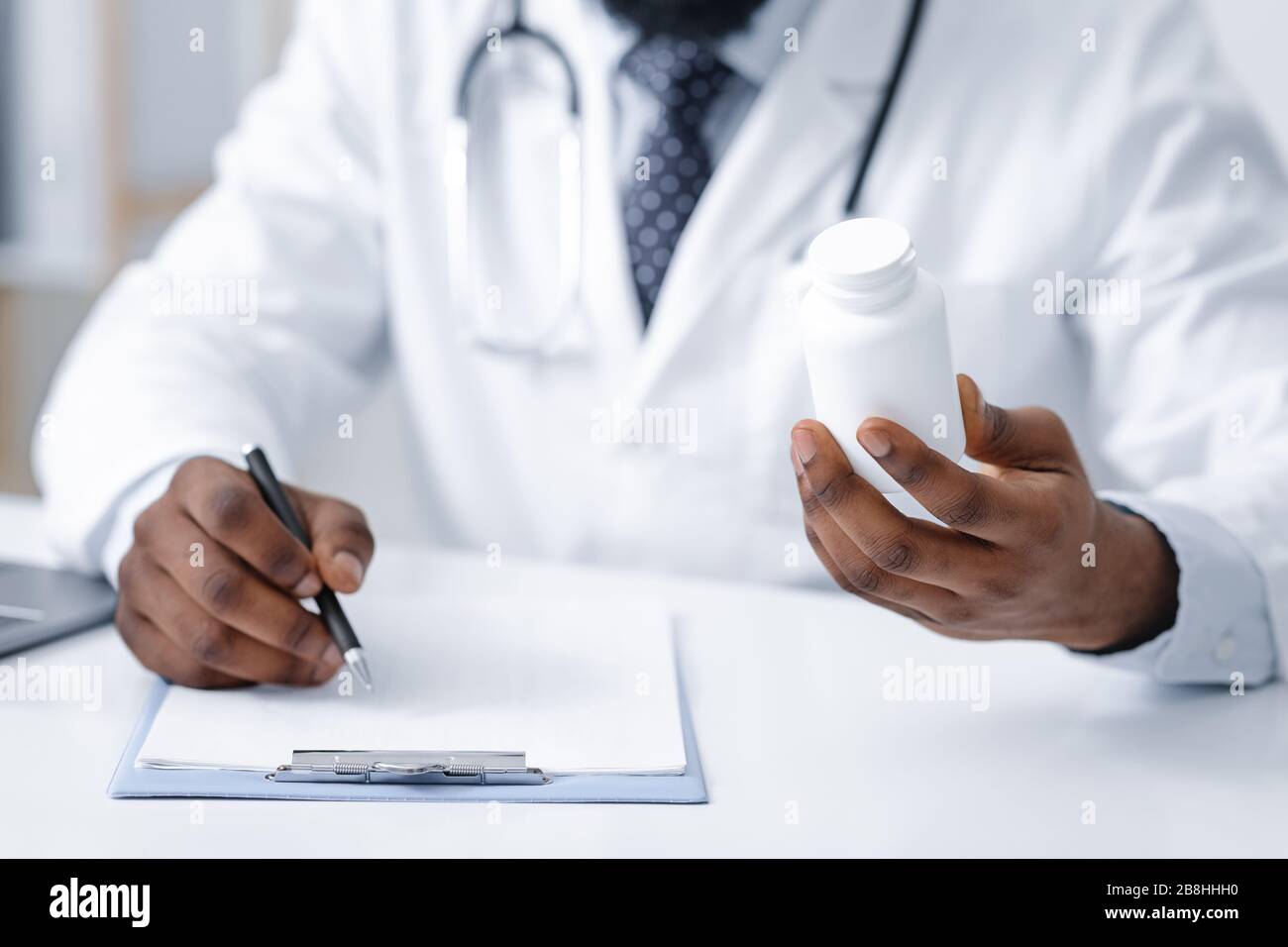 African general practitioner holding pills box and writing Stock Photo ...