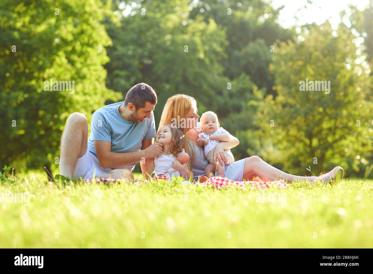 Happy family sitting on the green grass are playing in the park Stock ...