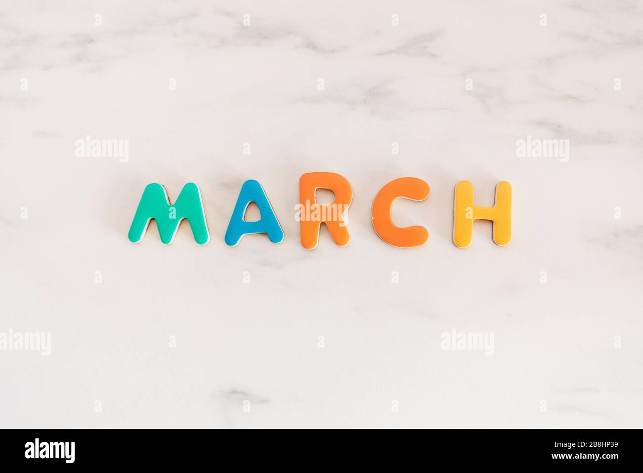 March word written with colorful letters on white marble stone ...