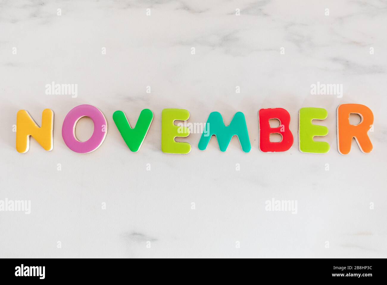 November word written with colorful letters on white marble stone ...