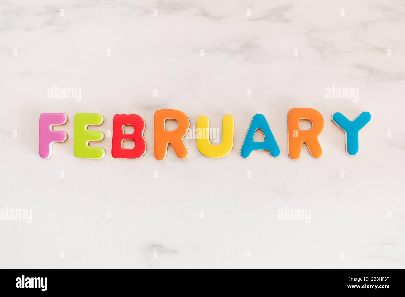 February word written with colorful letters on white marble stone ...
