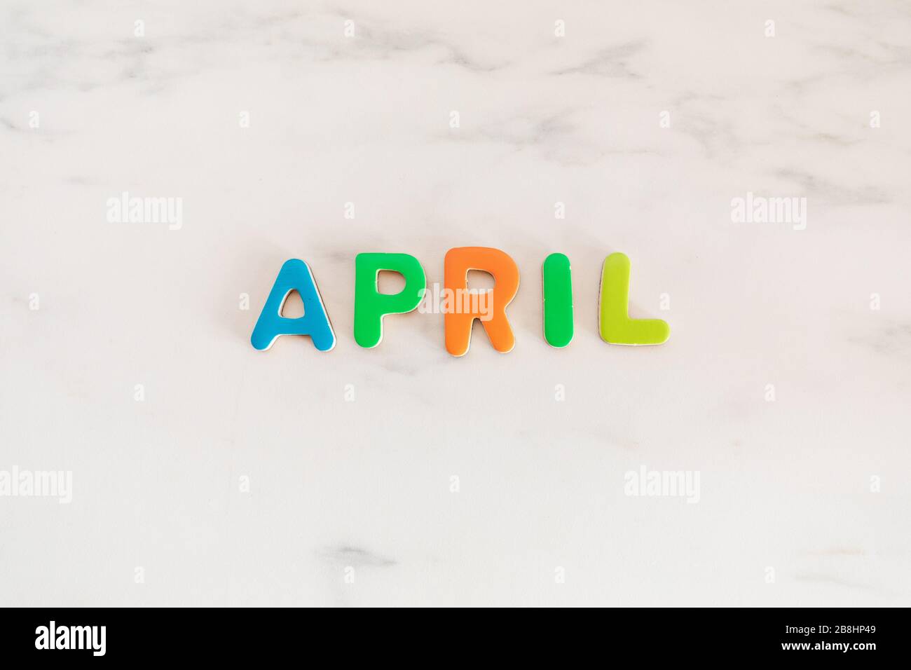 April word written with colorful letters on white marble stone ...