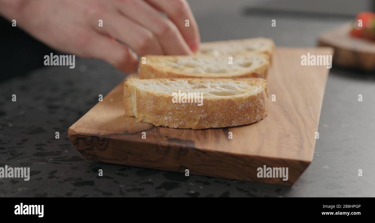 man hand put ciabatta slices on olive board, wide photo Stock Photo - Alamy