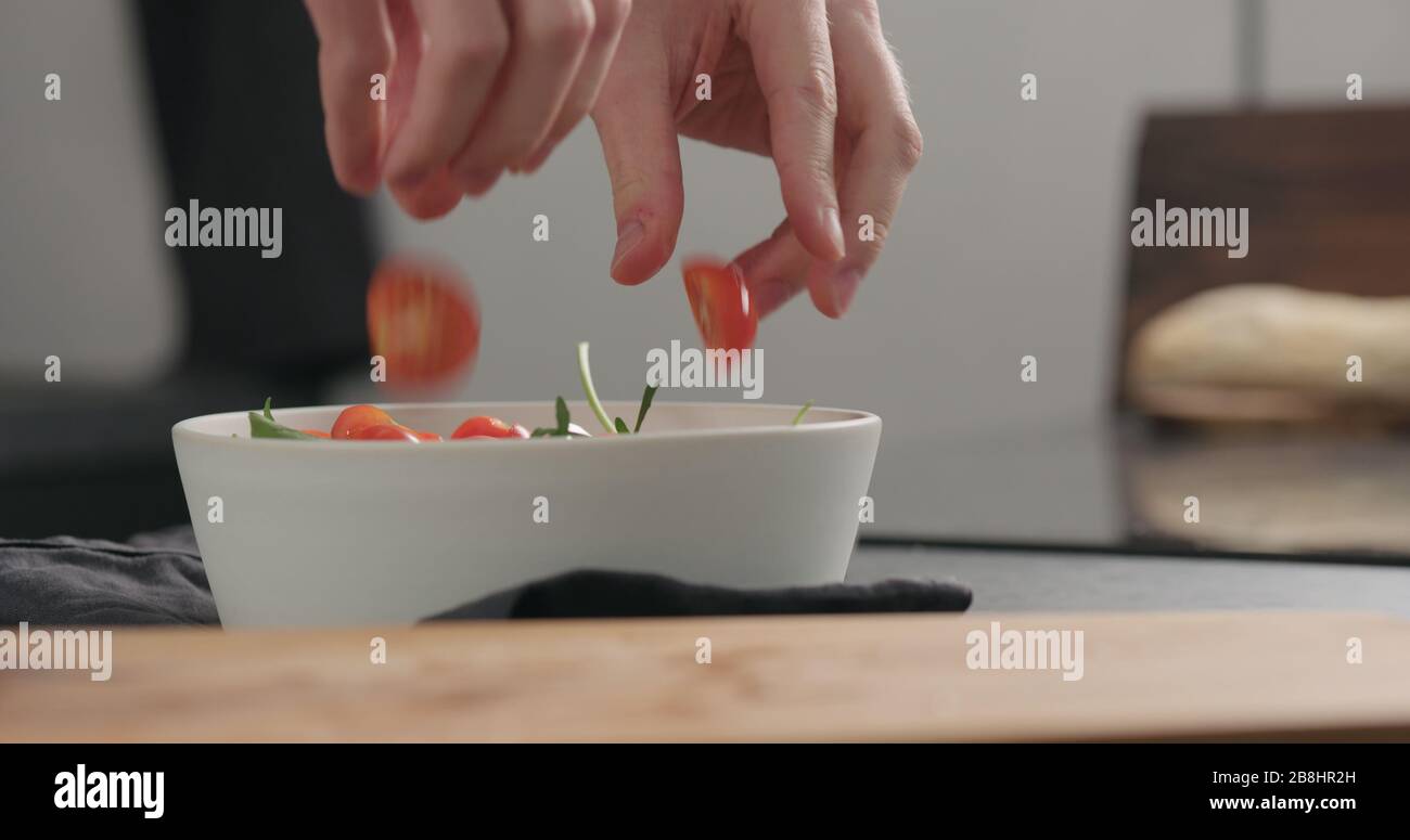 man add tomato halves into white bowl to make a salad, wide photo Stock ...