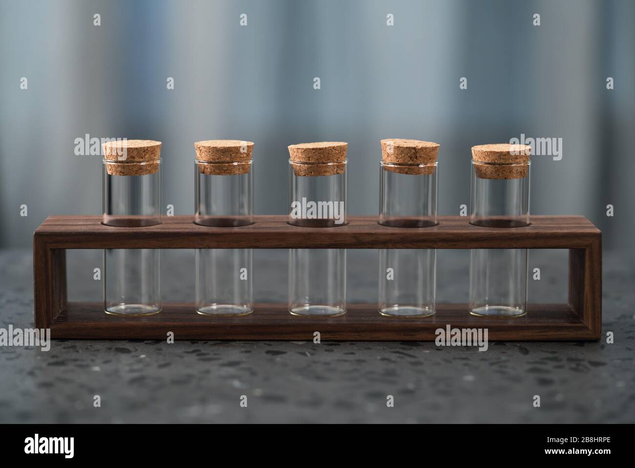 walnut holder with glass tubes for spices on concrete surface, shallow ...