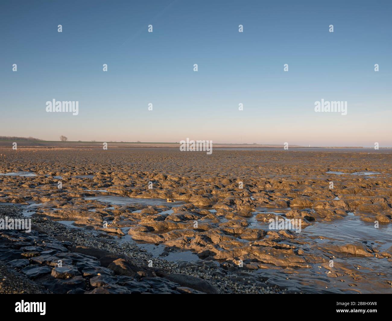 Aerial view of horizon over sea, with mounds of mud in the foreground ...