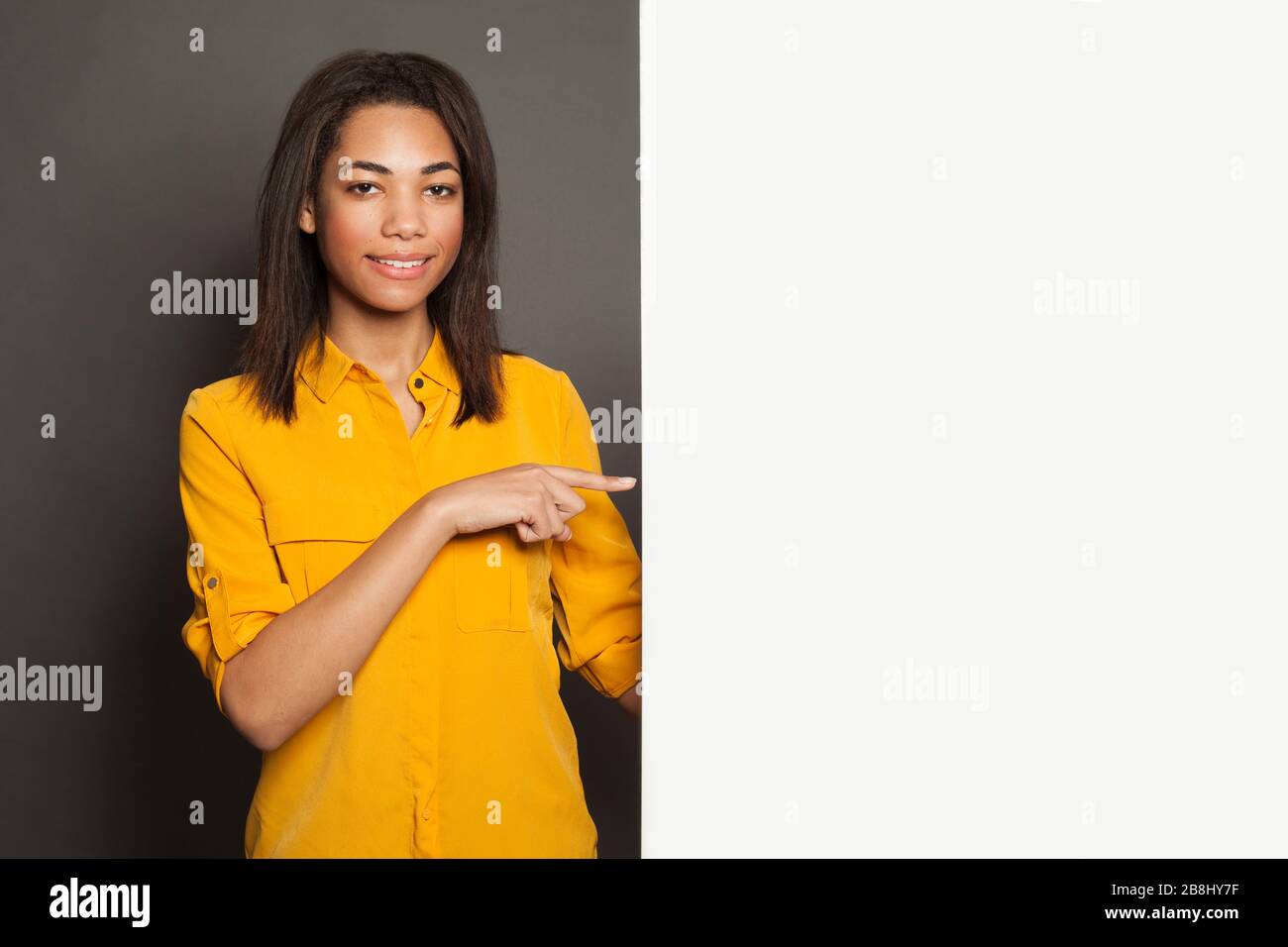 Cute black woman student pointing finger at empty banner background ...