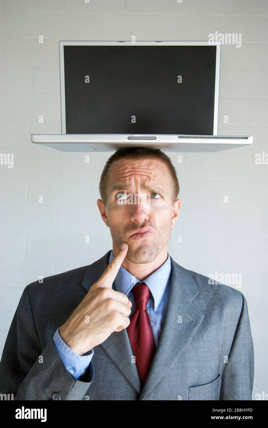 Businessman thinking while balancing a blank screen laptop computer on ...